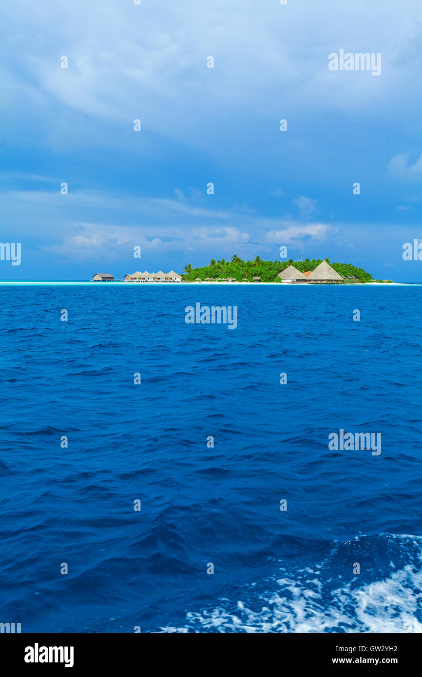 Small atoll island with traditional wooden bungalows and Indian ocean ...