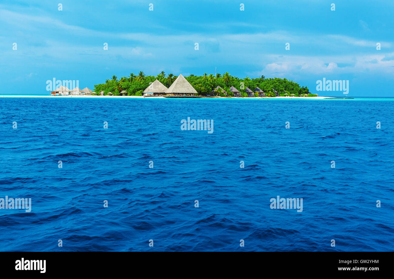 Small atoll island with traditional wooden bungalows and Indian ocean ...