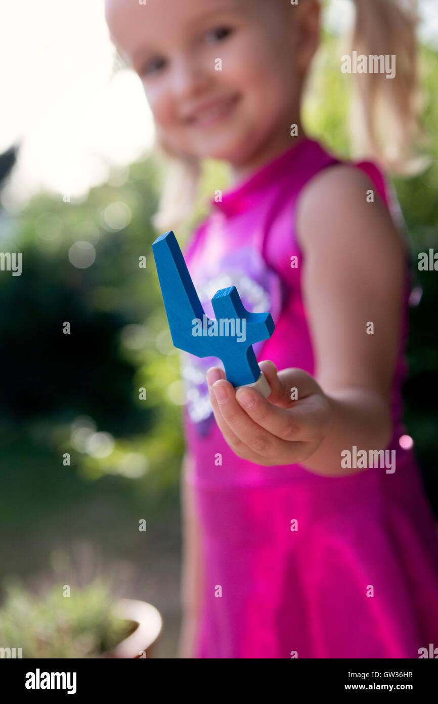 Smiling child holding blue number four Stock Photo - Alamy
