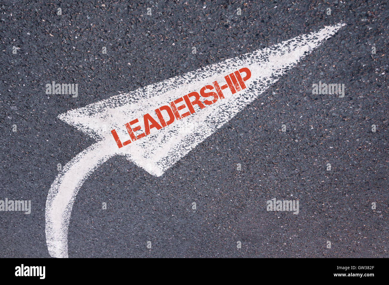 Directional white painted arrow with word LEADERSHIP over road surface ...