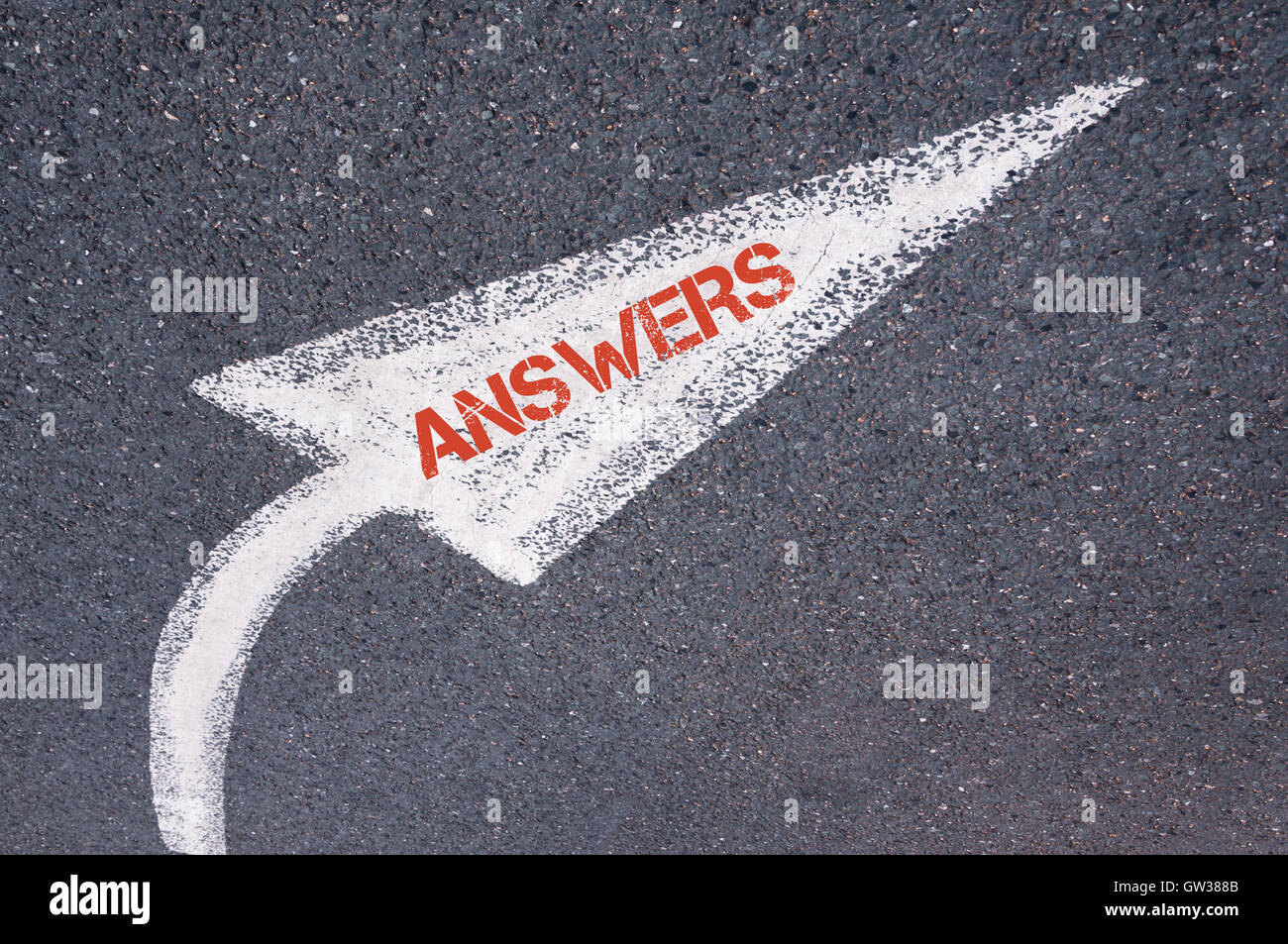 Directional white painted arrow with word ANSWERS over road surface ...