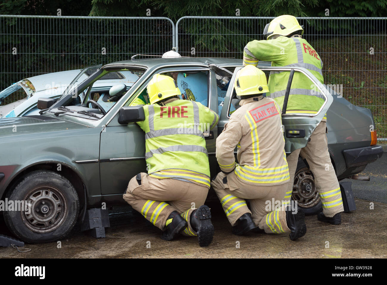 Fire men simulate a car crash rescue by cutting the doors off the car ...