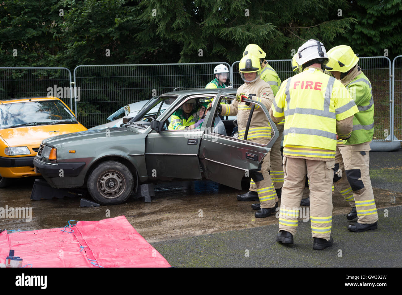 Fire men simulate a car crash rescue by cutting the doors off the car ...