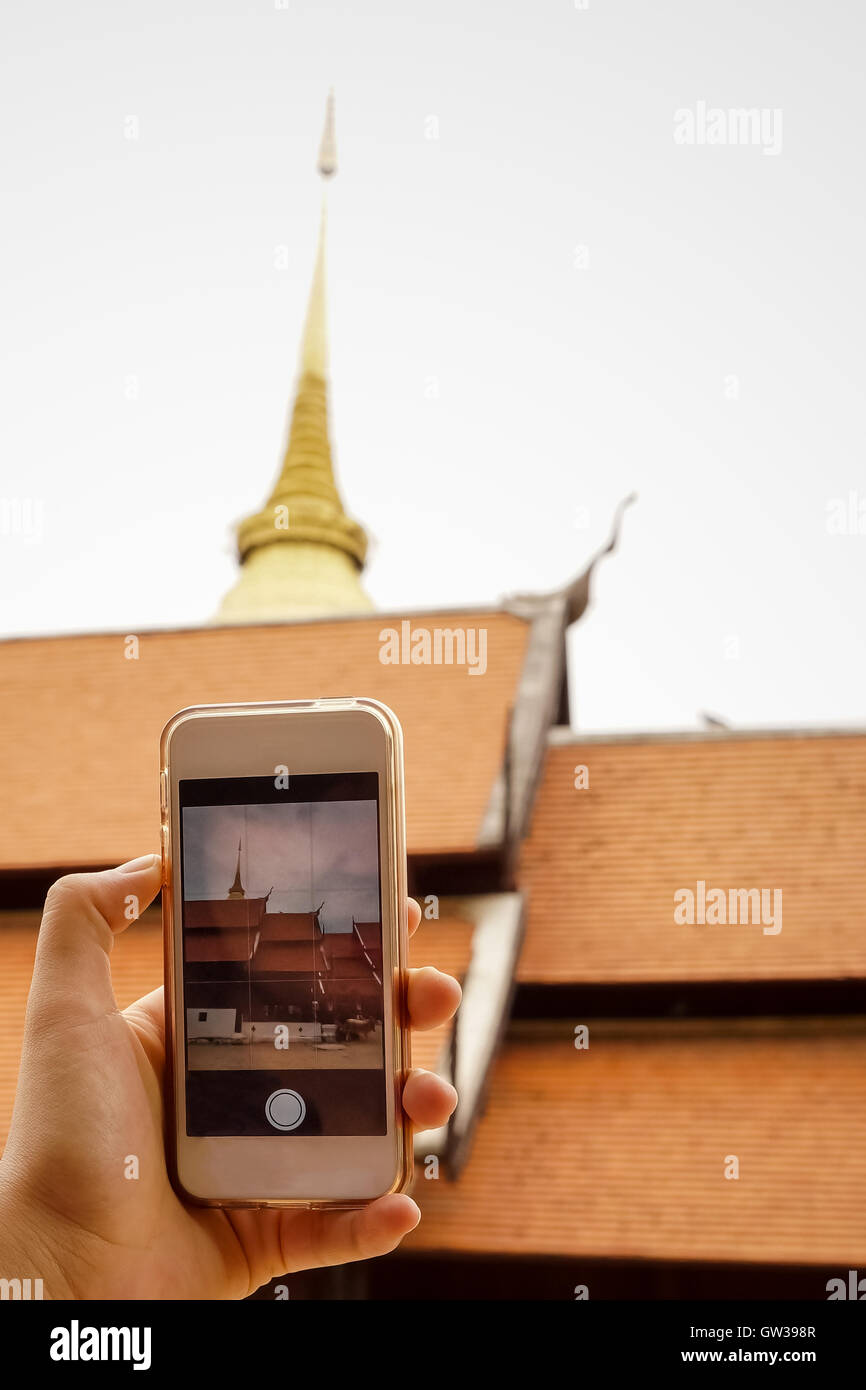 Hand holding smart phone (Mobile Phone) with pagoda and temple roof in ...