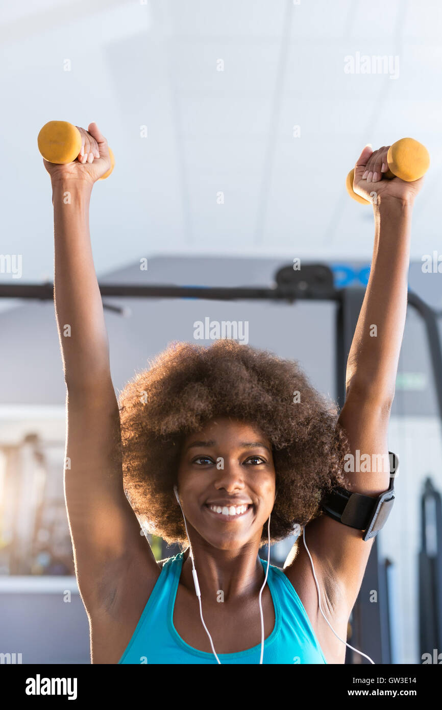 Happy healthy young African American woman working out in a gym with a ...