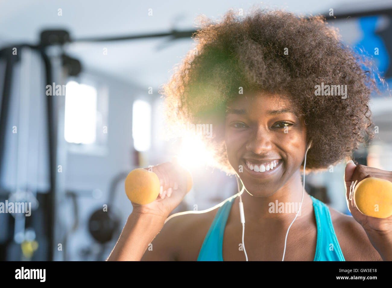 Happy healthy young African American woman working out in a gym with a ...