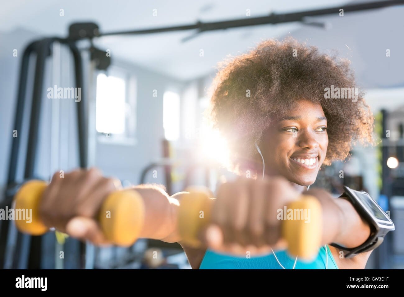 Happy healthy young African American woman working out in a gym with a ...
