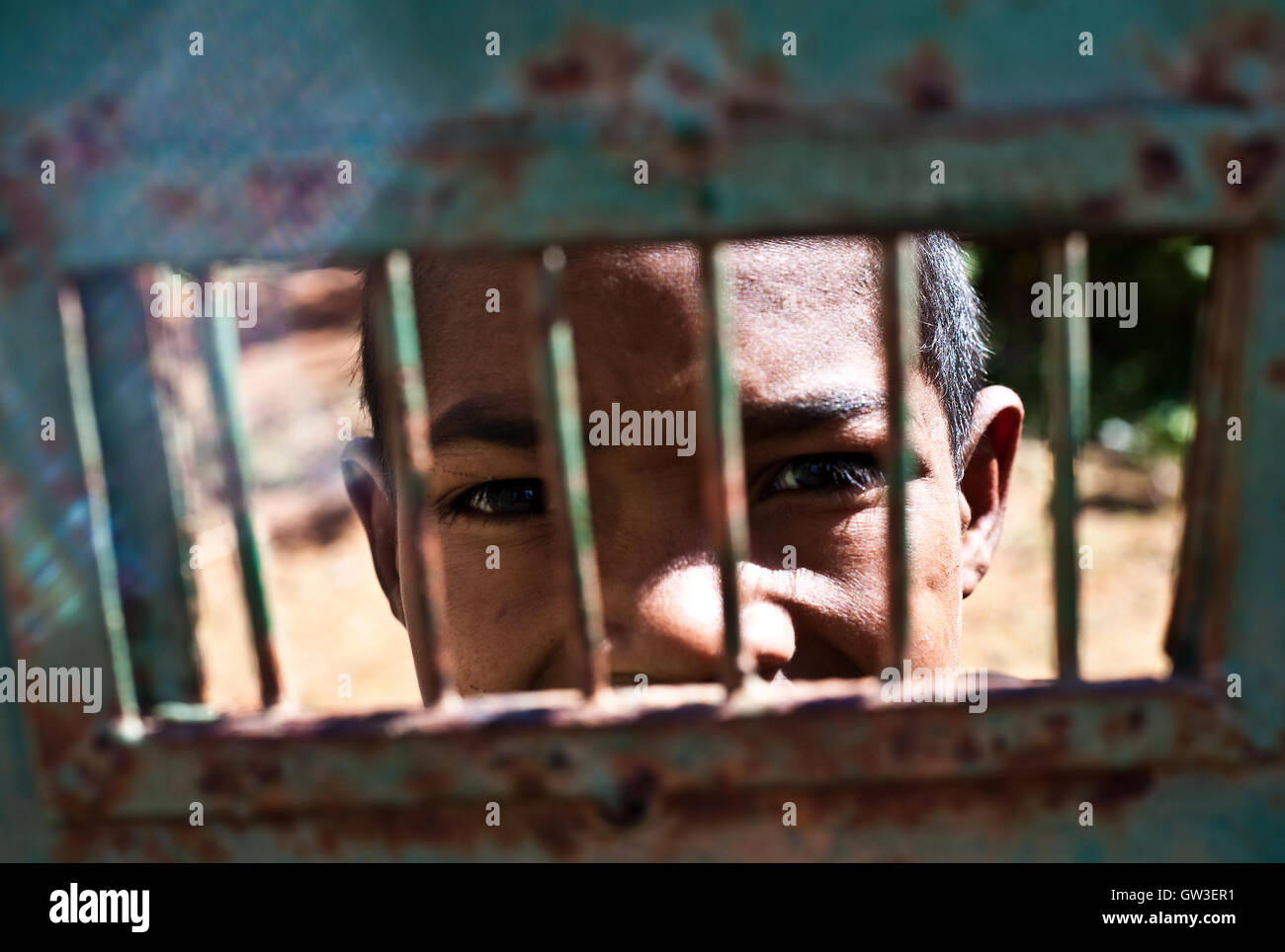 Suspicious boy looking through a grid ( Madagascar Stock Photo - Alamy