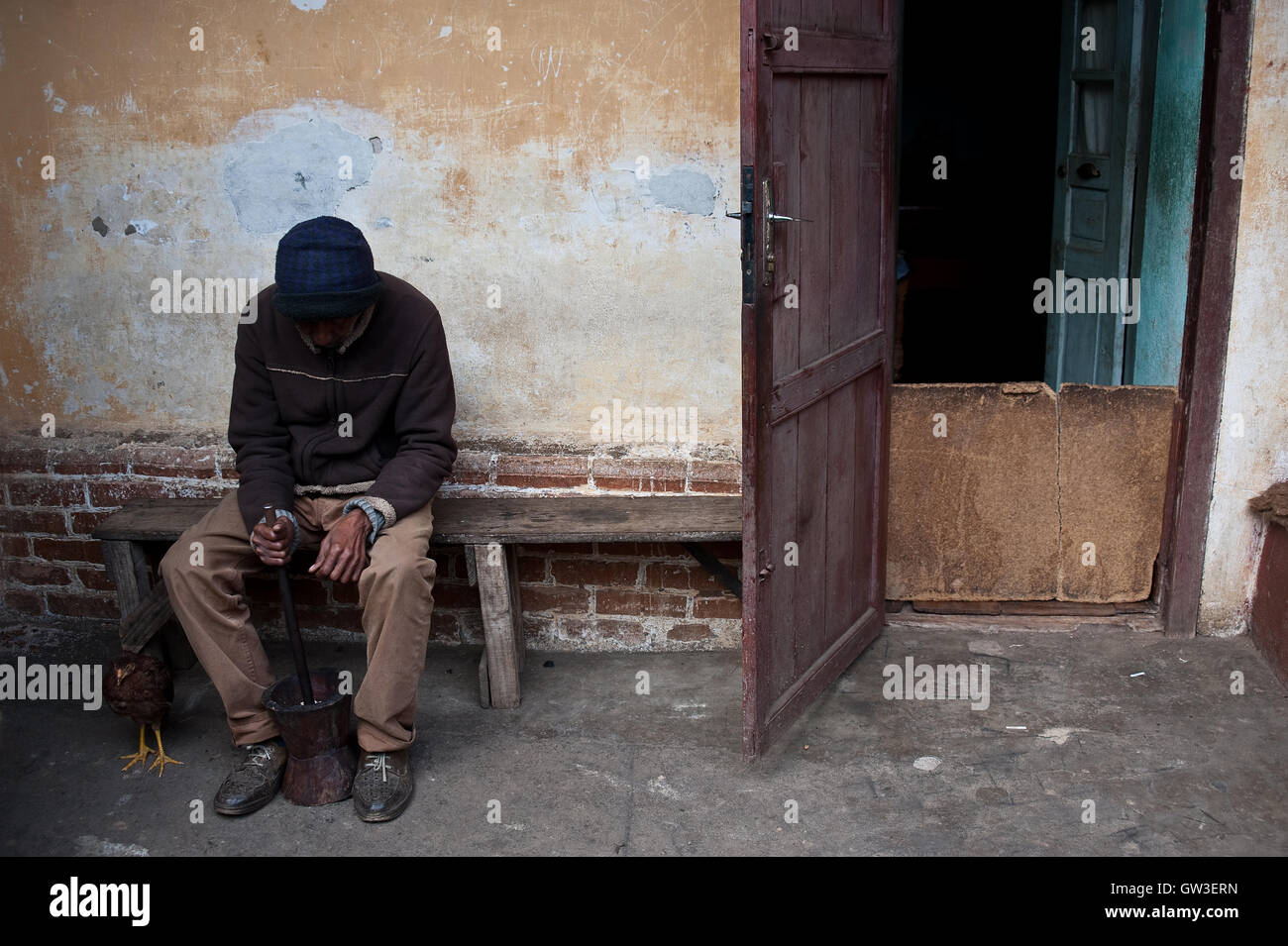 Man crushing peanuts outside his house ( Madagascar Stock Photo - Alamy