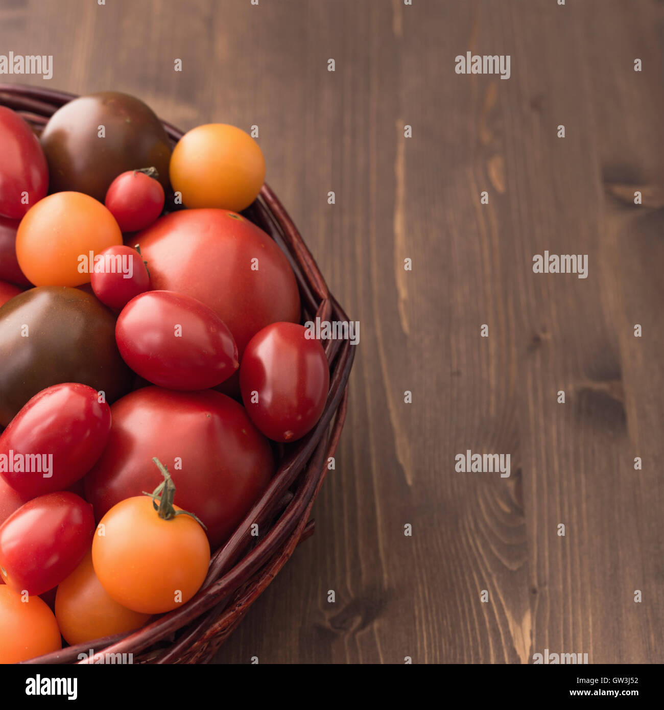Multi-colored tomatoes at left side of wooden background Stock Photo ...