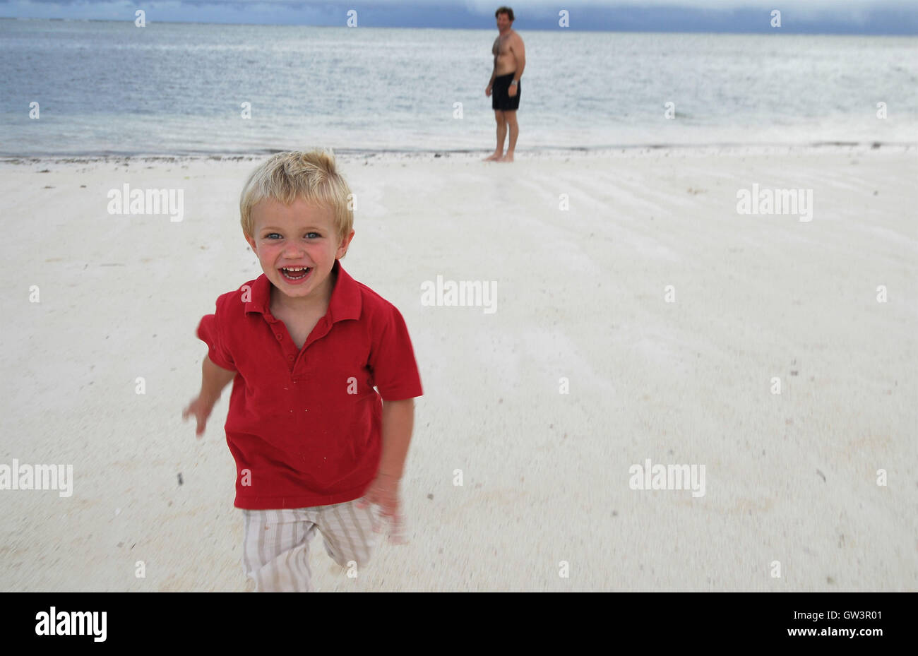 Boy on the beach laughing with father Stock Photo - Alamy