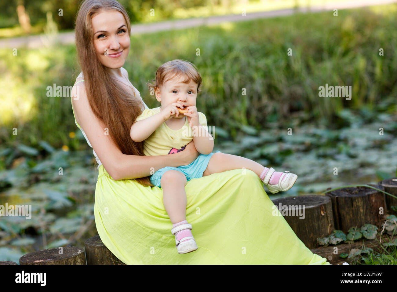 Happy mother and daughter on stump in park Stock Photo - Alamy