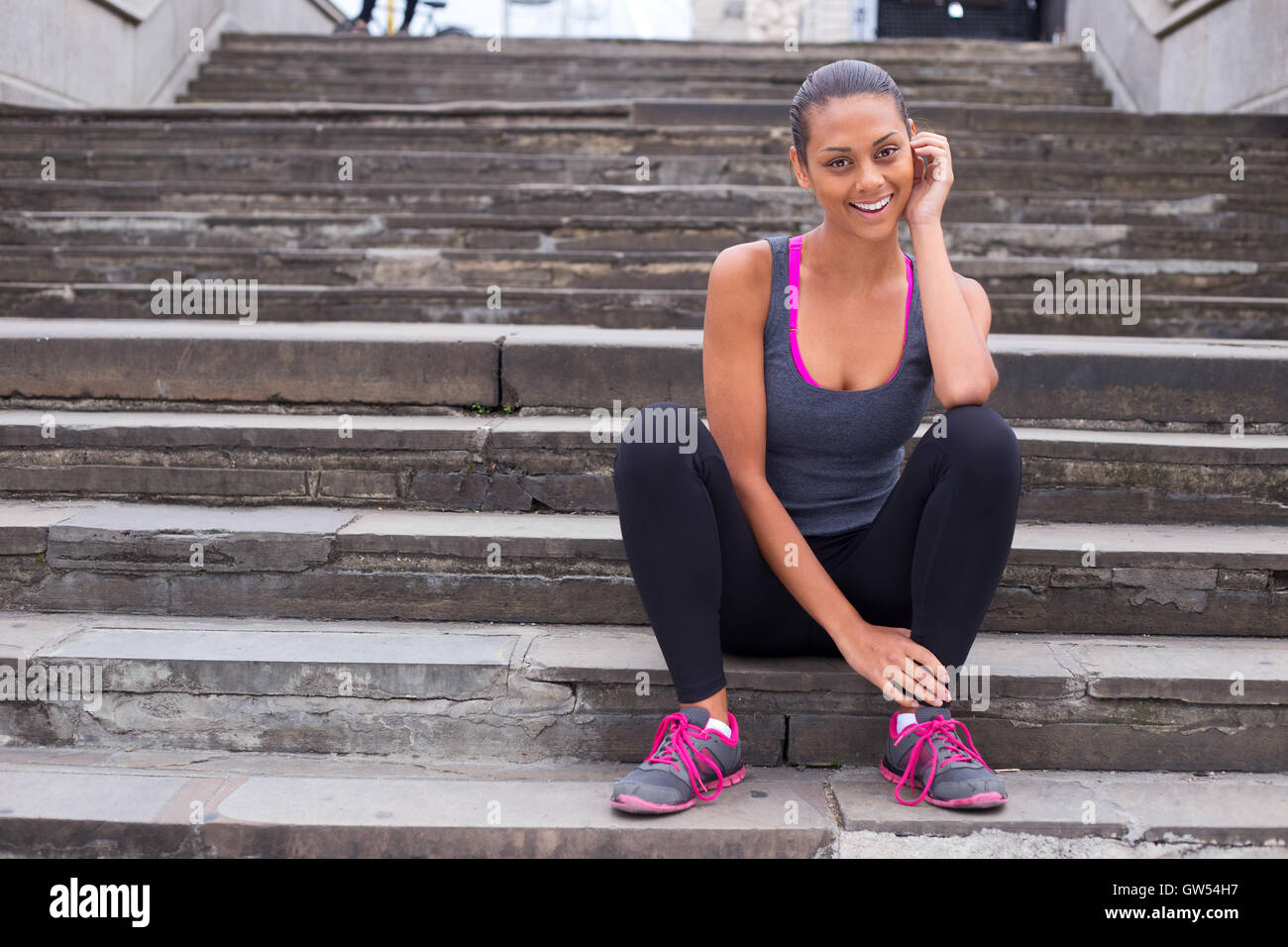 A happy girl sitting on steps relaxing after exercising Stock Photo - Alamy