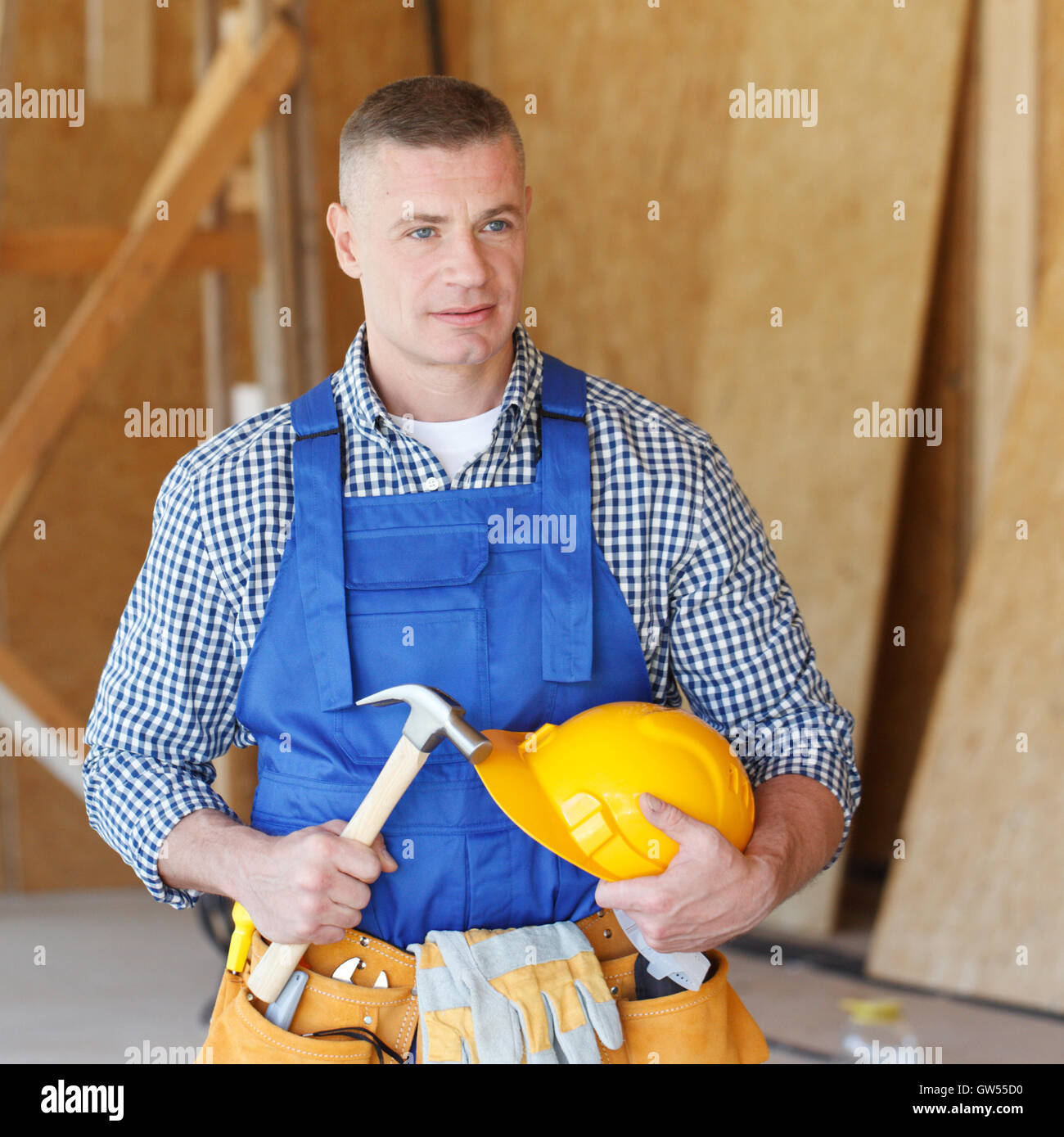Construction worker with hammer in hand and tools at construction site ...