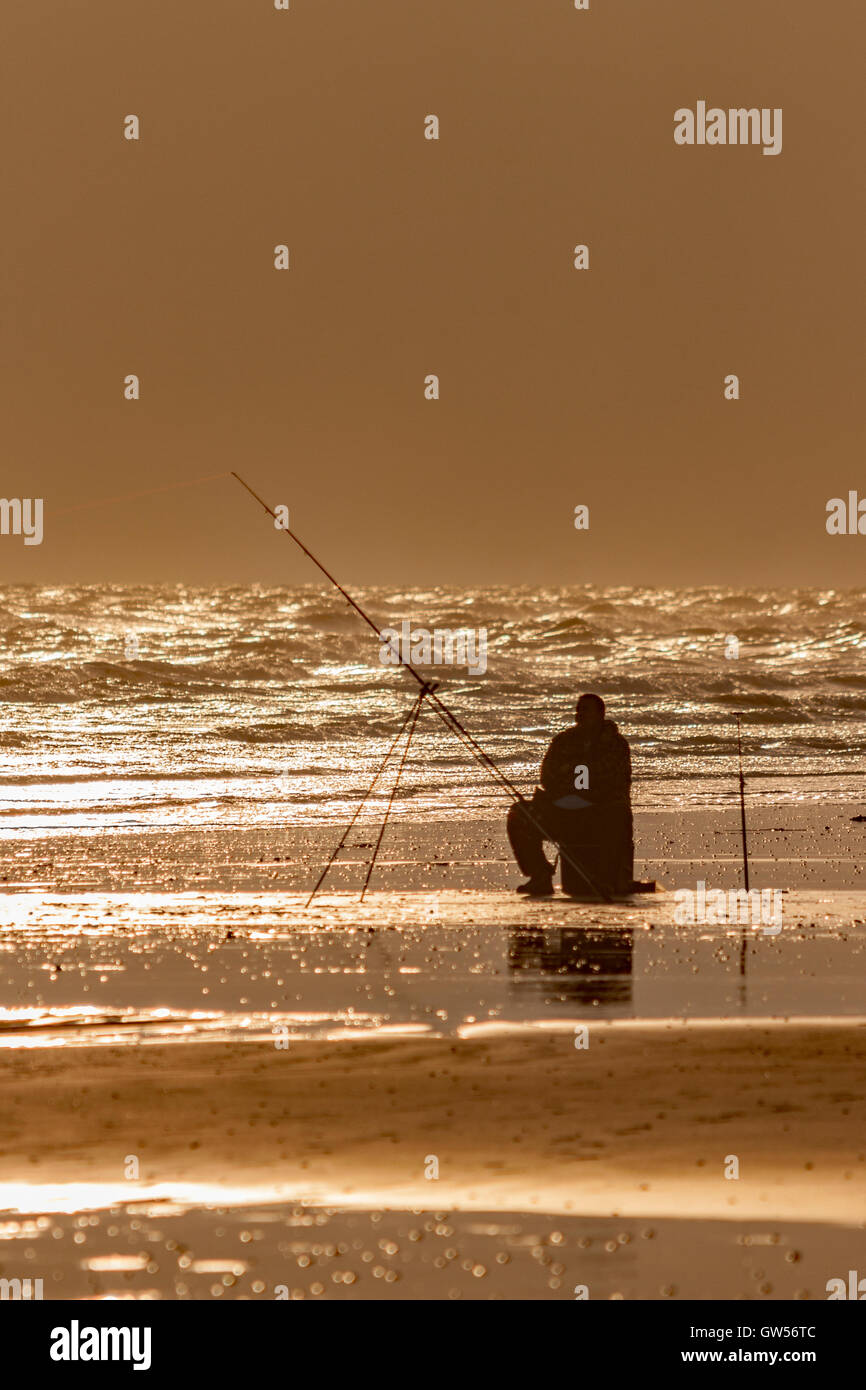 Angler sea fishing on a beach at sunset in the UK Stock Photo - Alamy