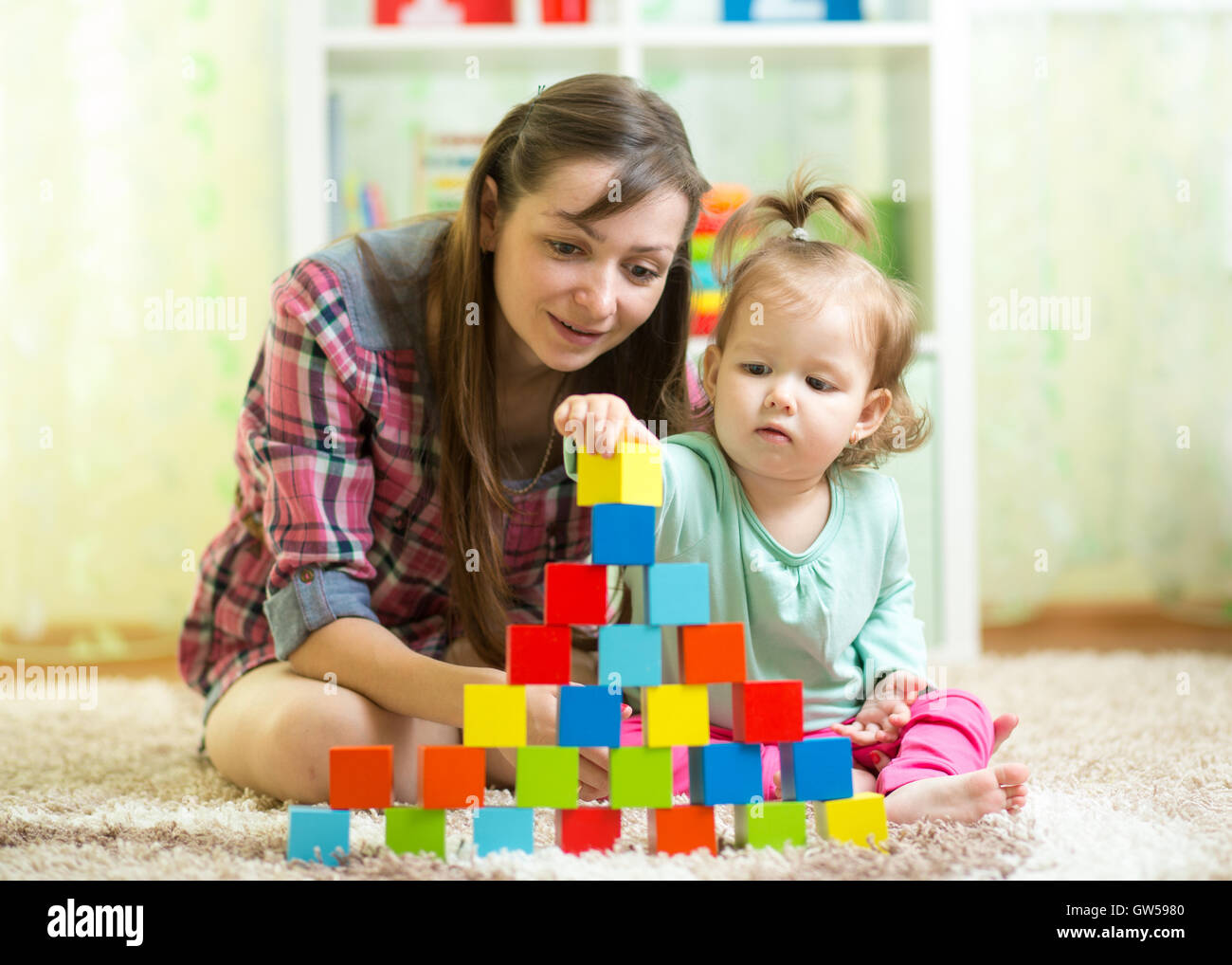 kid toddler and mother build tower playing wooden toys at home or ...