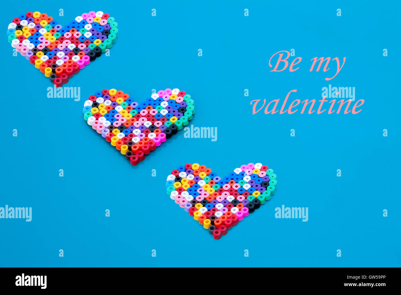 Be my valentine writing in pink script on blue background with three ...