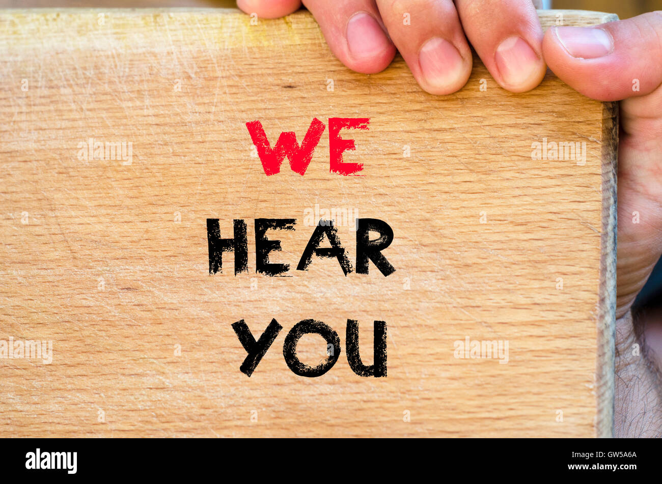 Human hand over wooden background and we hear you text concept Stock ...