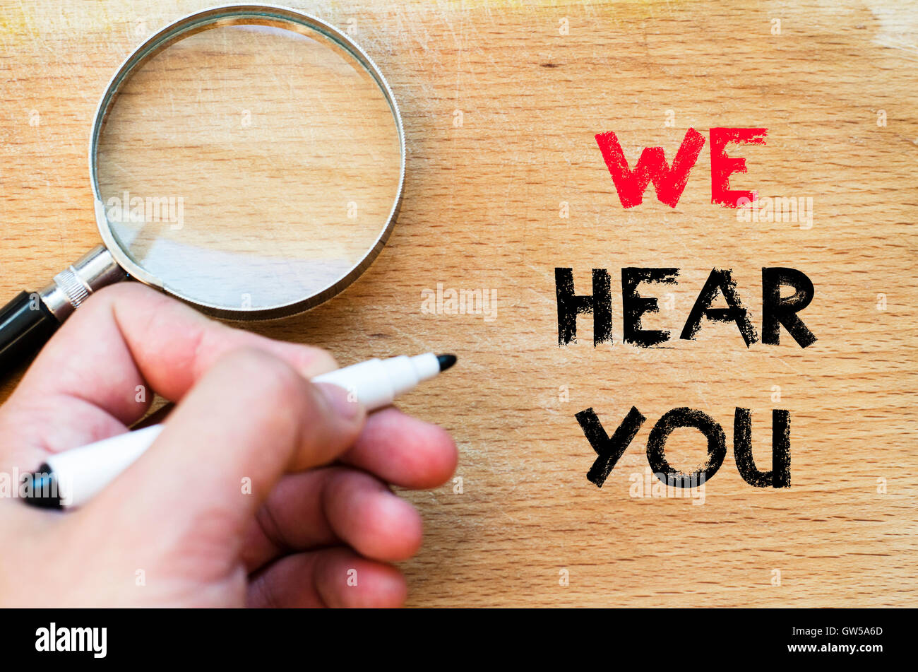 Human hand over wooden background and we hear you text concept Stock ...