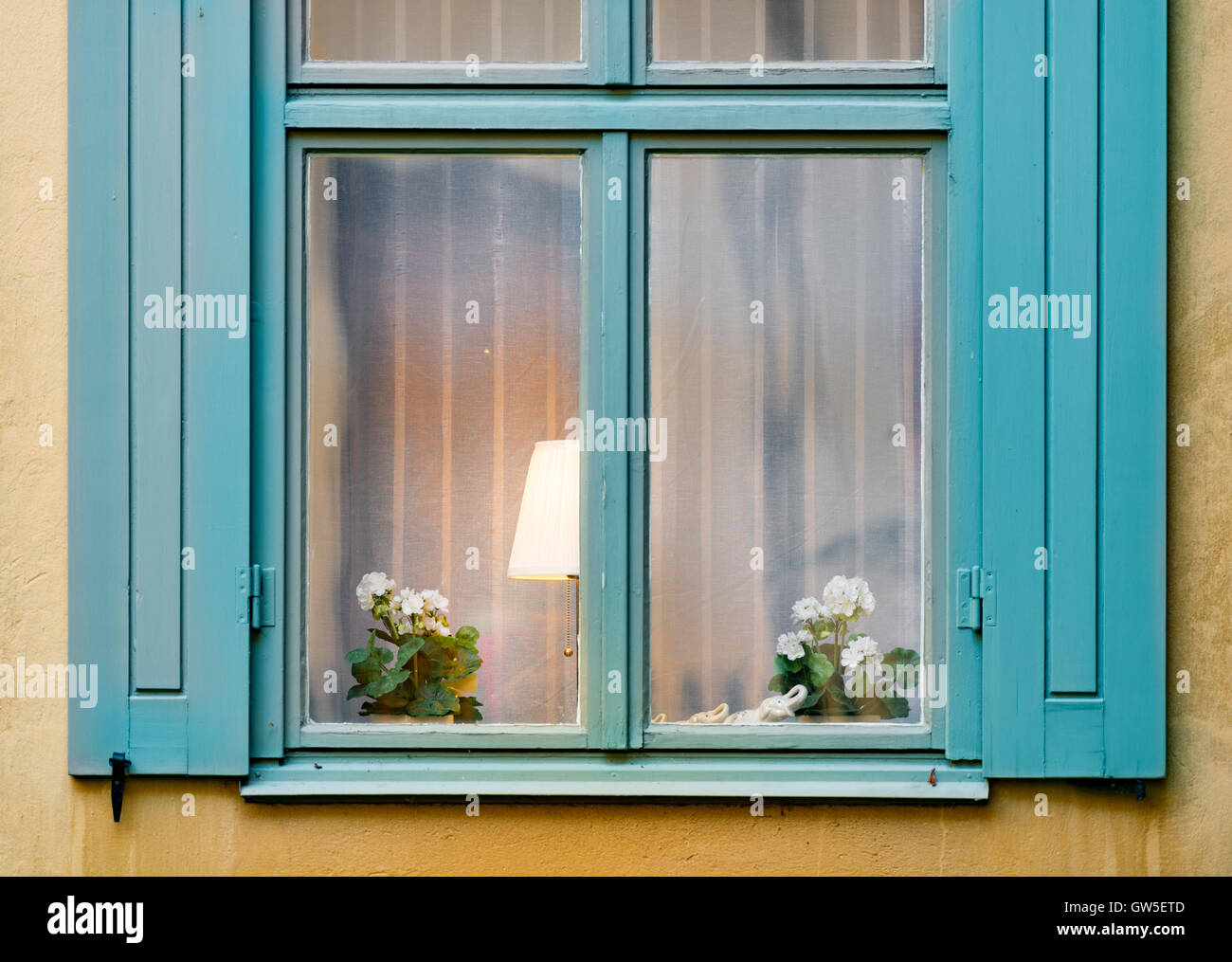 Details of old house window with flower and lamp inside. Yellow wall of ...