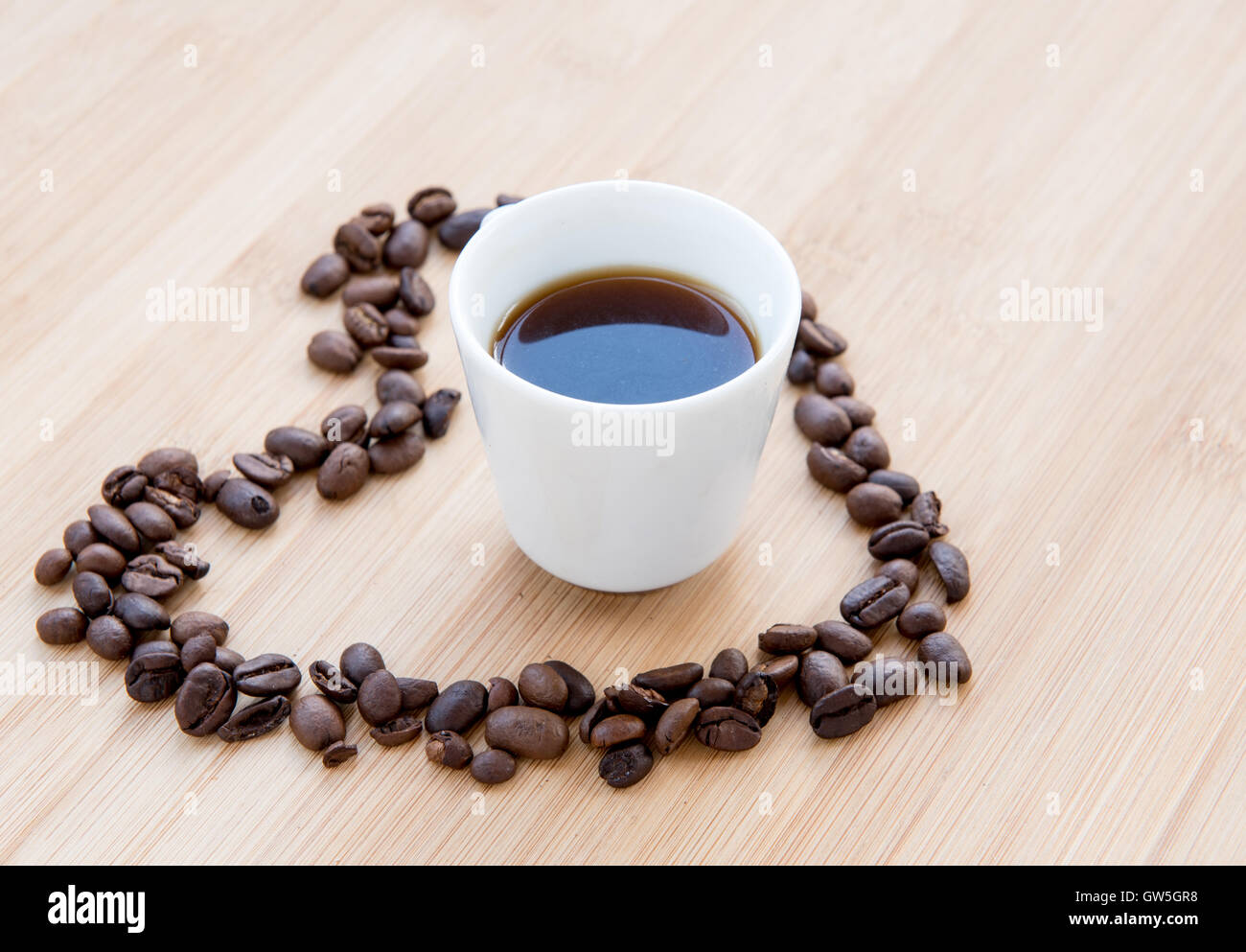 Coffee beans in the shape of heart symbol and a cup of black espresso ...