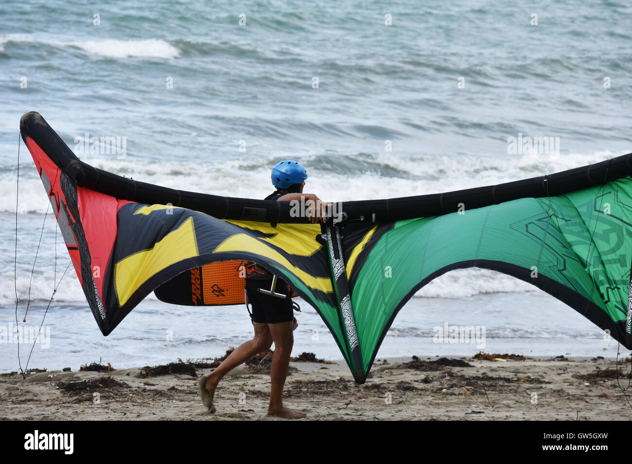 Kitesurfer wearing helmet carrying colourful kite on beach Stock Photo ...