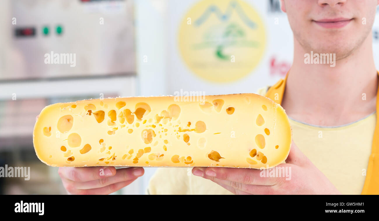 Alpine cheese for sale offered by a salesman Stock Photo - Alamy