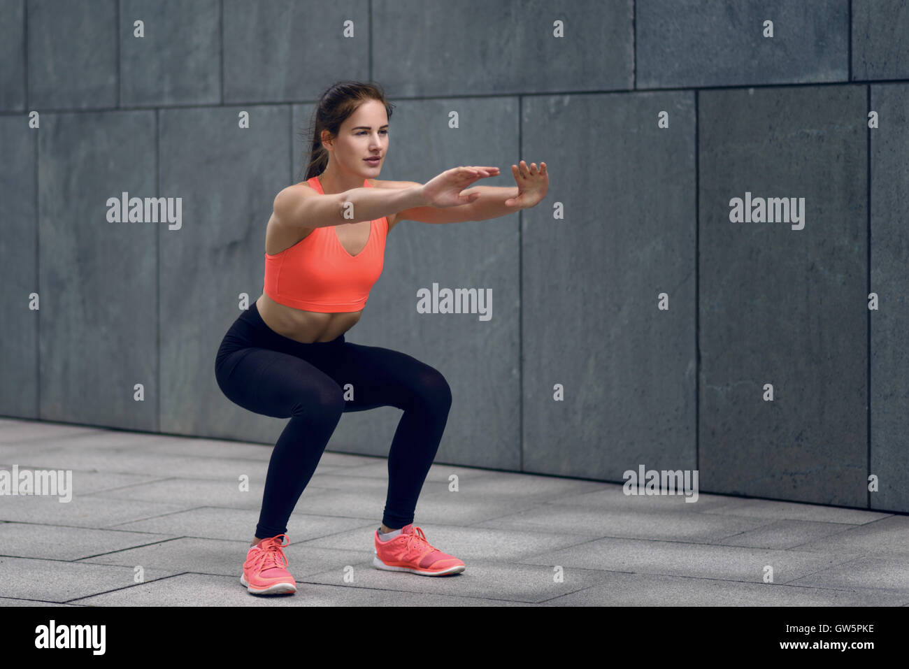 Fit young woman doing squats, strengthening her core, working out on a ...