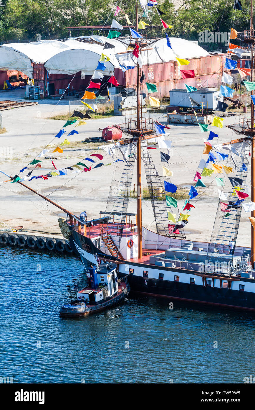 Tugboat docking a three masted party boat with colorful pennants Stock ...