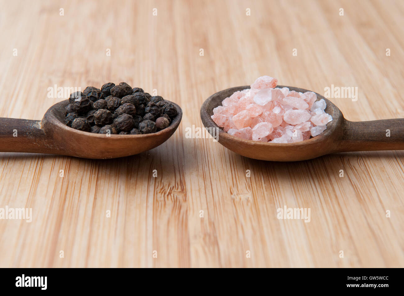 Salt and pepper seasonings of pepper corns and rock salt on wooden ...