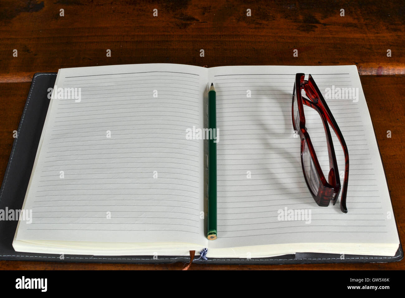 An open journal with blank pages from above, with pencil, and readers ...