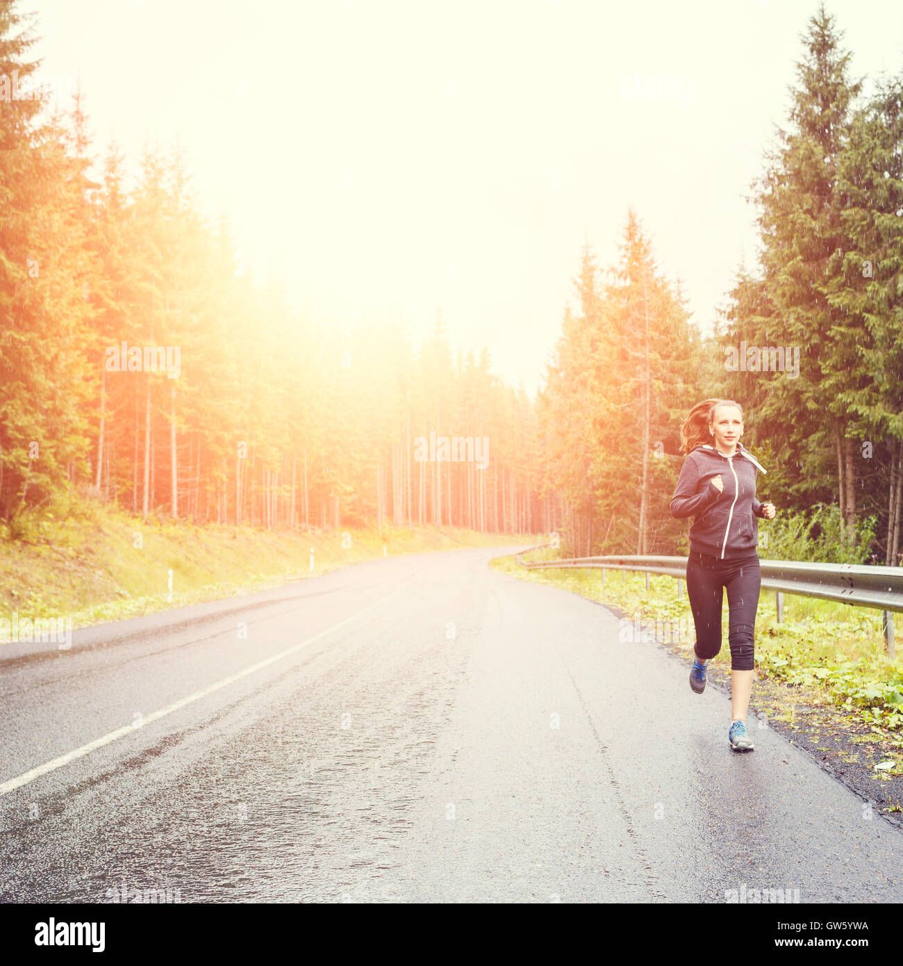 Young fitness woman with long hair running at the rainy morning in ...