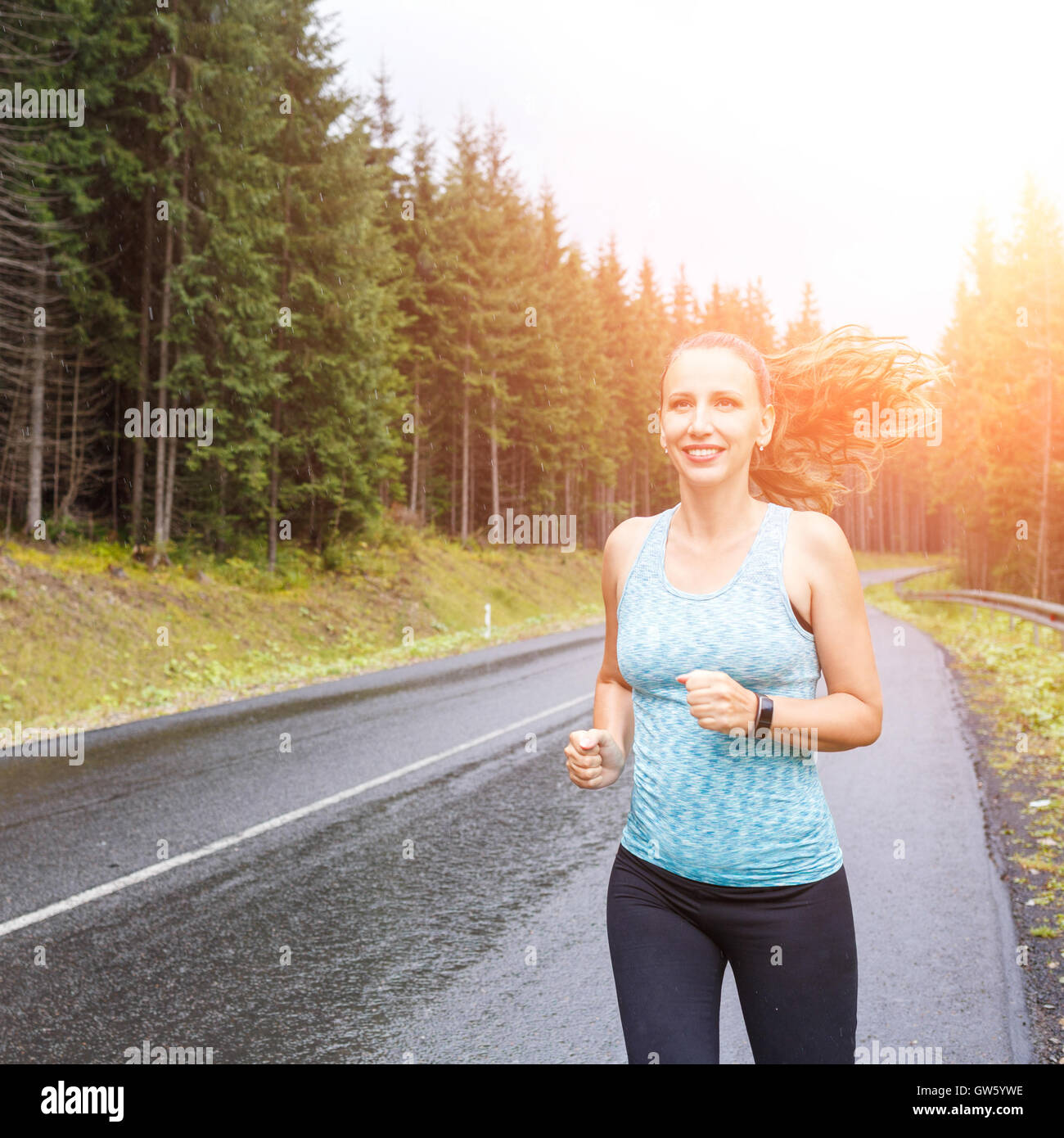 Young fitness woman with long hair running at the rainy morning in ...