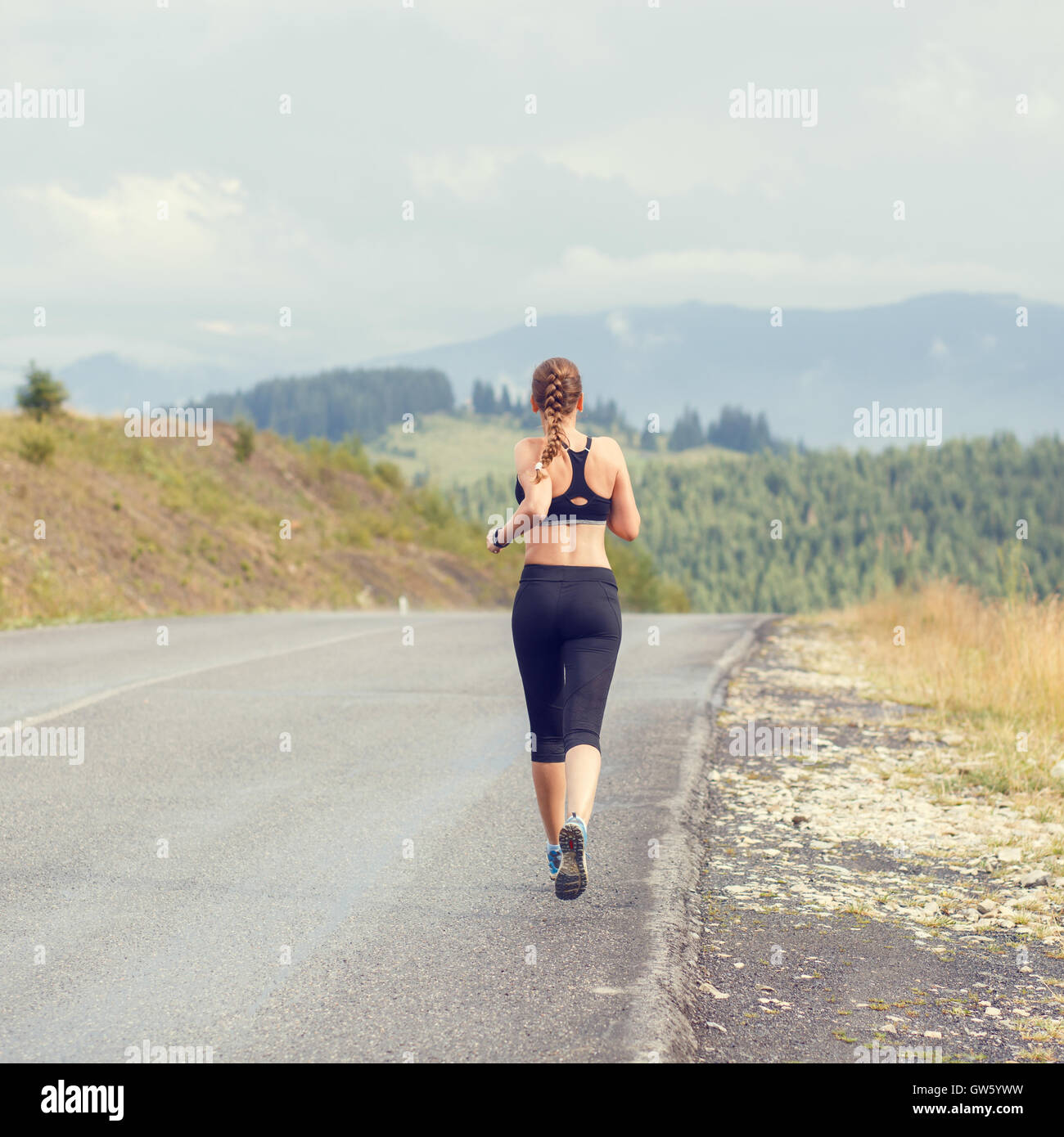 Young slim woman running on mountain road. Athletic girl in sportswear ...
