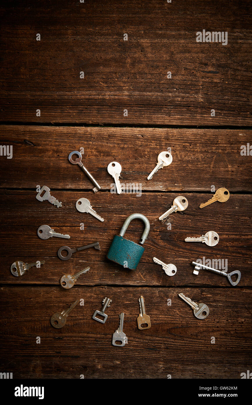 A lot of metal keys and a steel lock on a wooden boards Stock Photo - Alamy