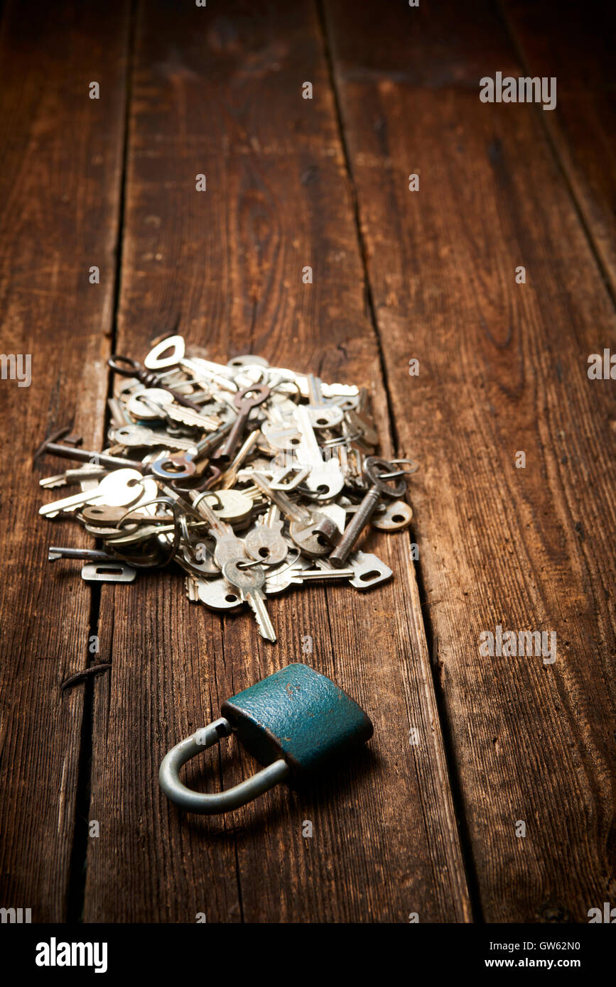Pile of keys and lock on a grunge wooden background Stock Photo - Alamy