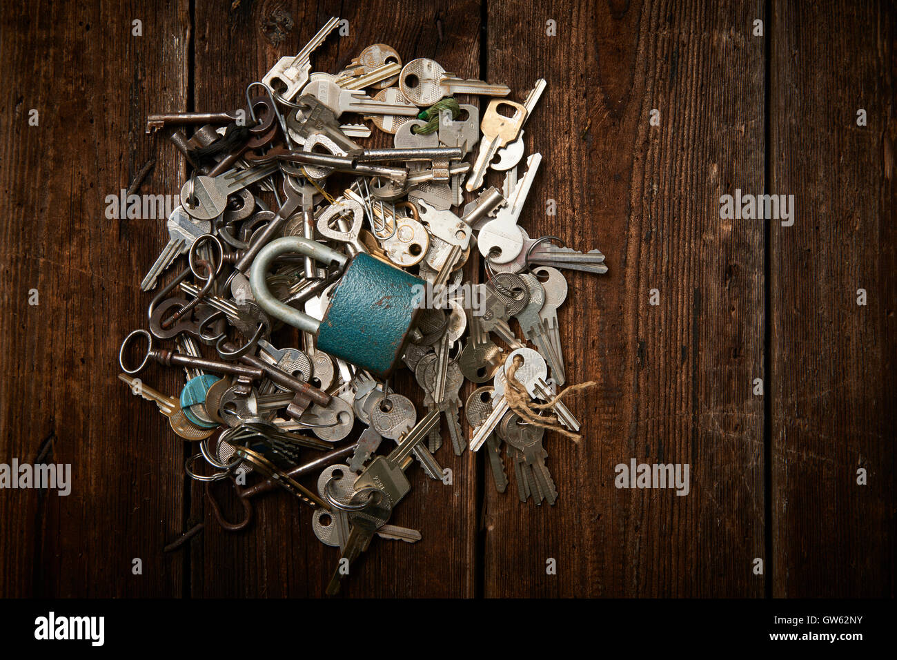 Pile of keys and lock on a grunge wooden background Stock Photo - Alamy