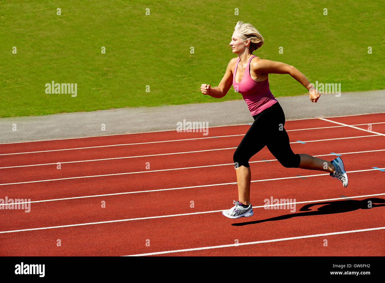 Athletic woman running on track Stock Photo - Alamy