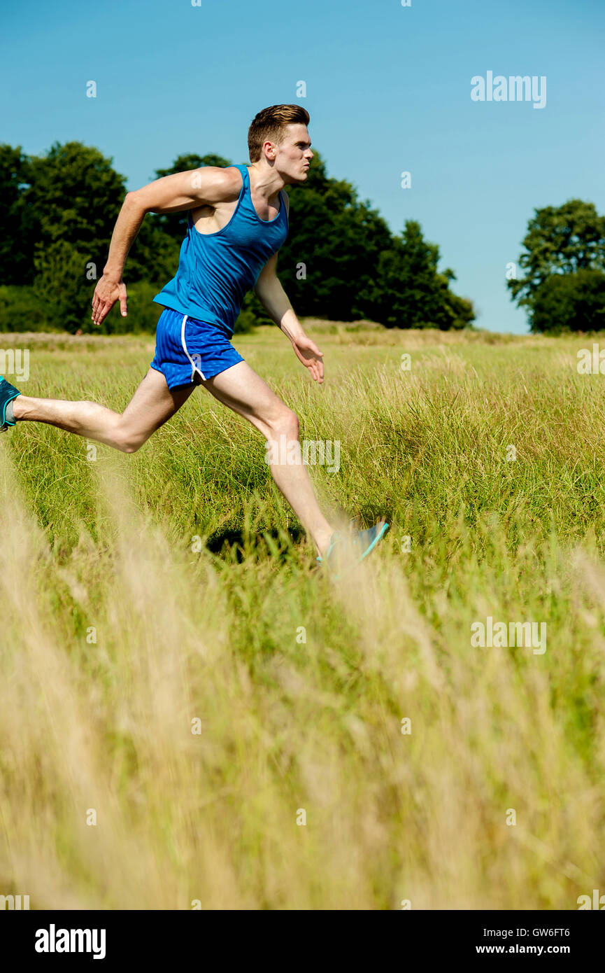 Young man running through meadows Stock Photo - Alamy