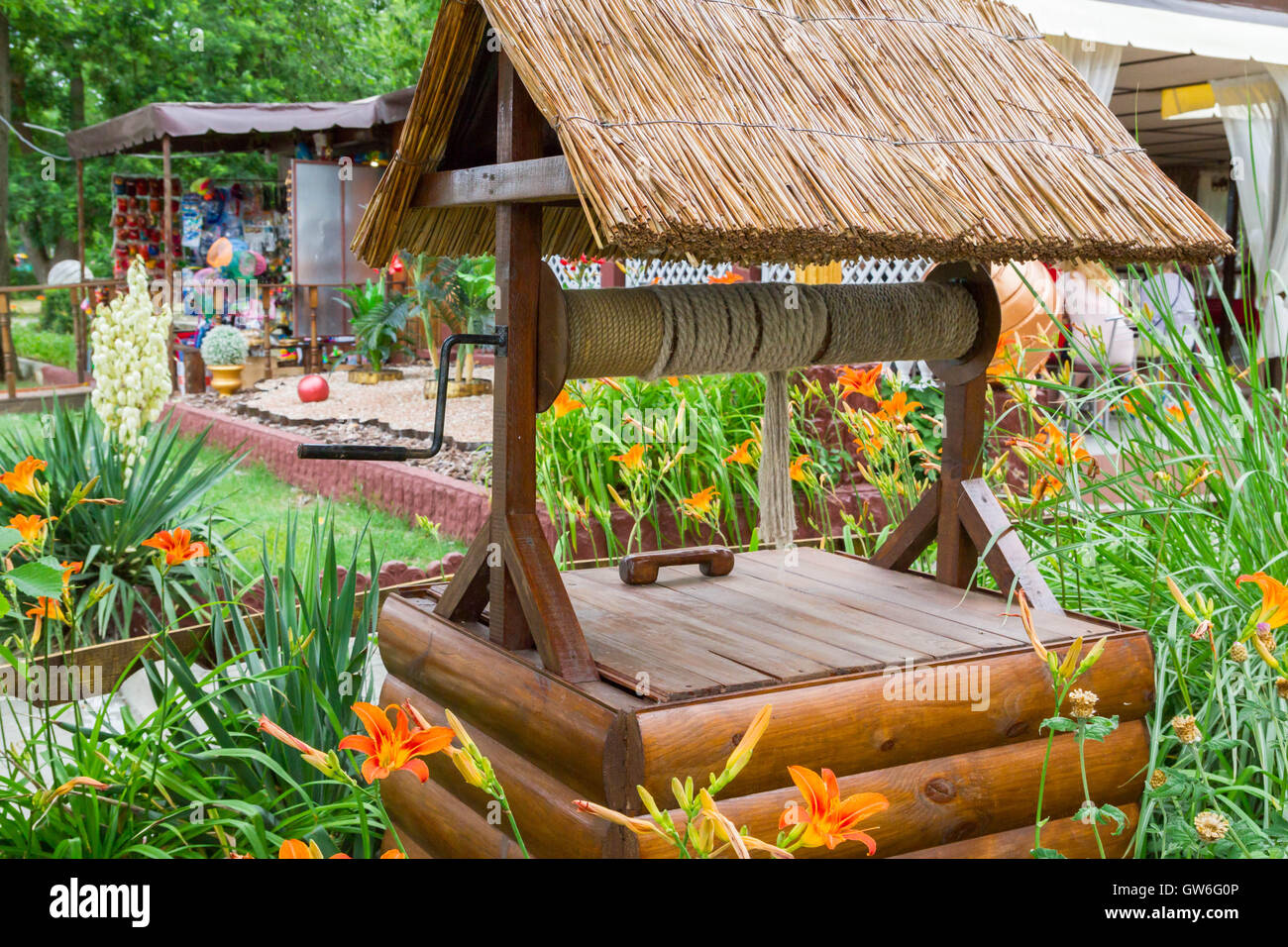 A wooden well with a thatched roof Stock Photo - Alamy