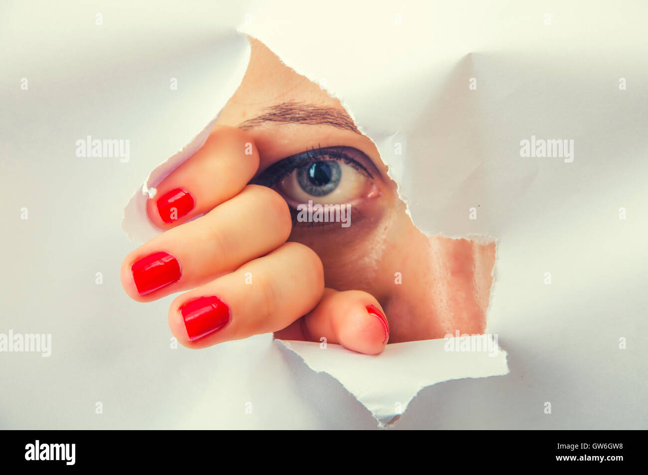 Woman looking through paper hole Stock Photo - Alamy