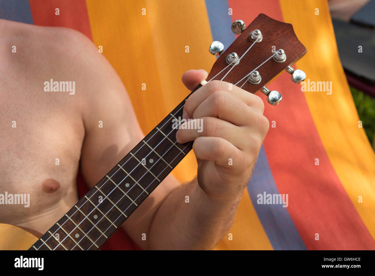 Detail of man relaxing on a hammock and playing ukulele Stock Photo - Alamy