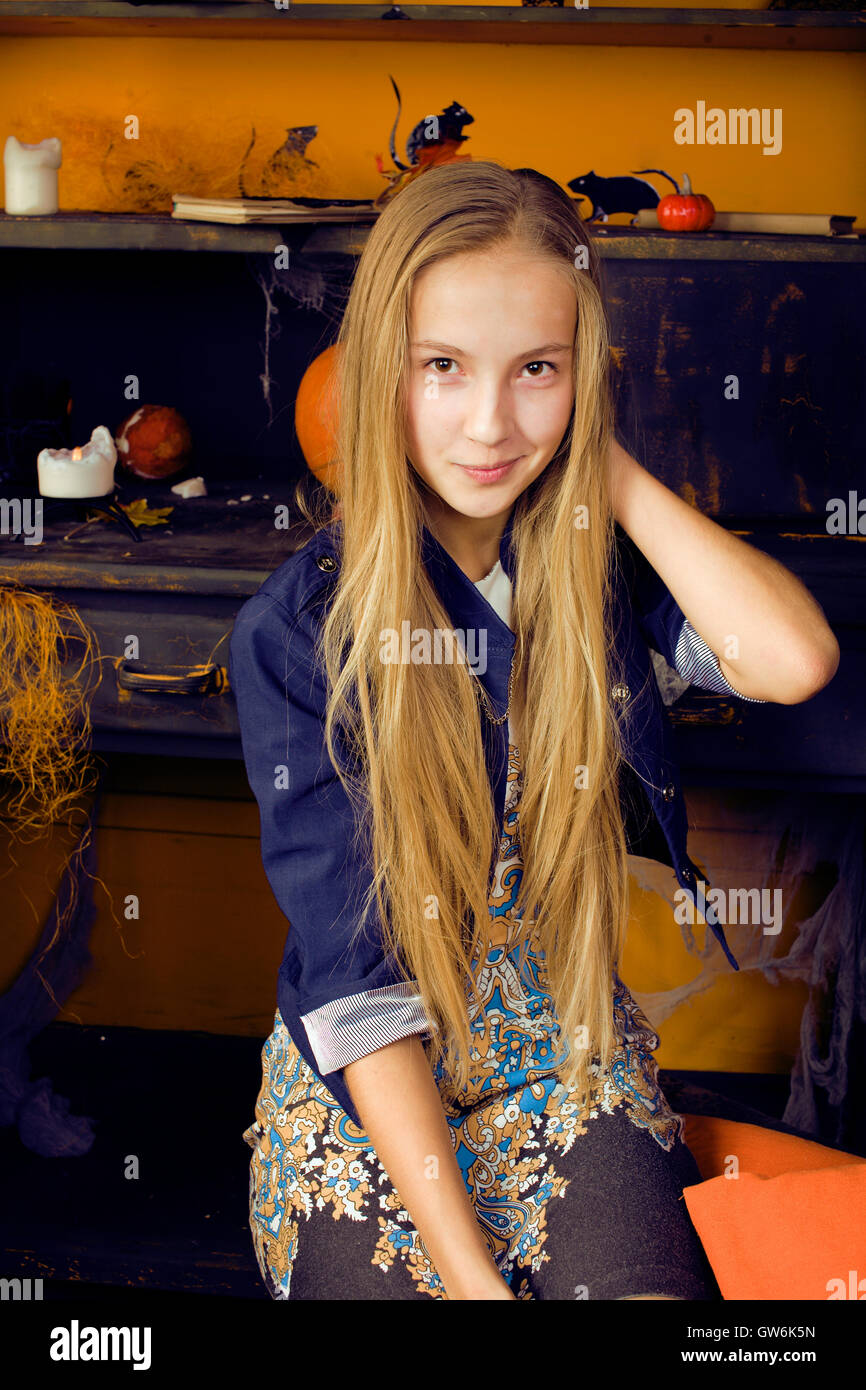 blond cute girl in halloween interior with pumpkin smiling, teen ...