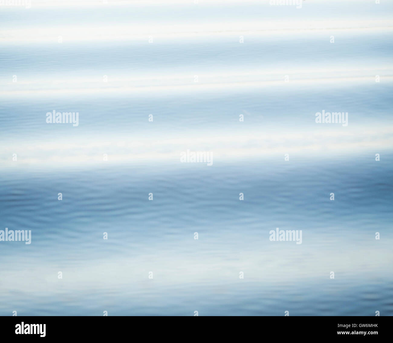 Smooth surface of the water with small ripples in soft blue as ...