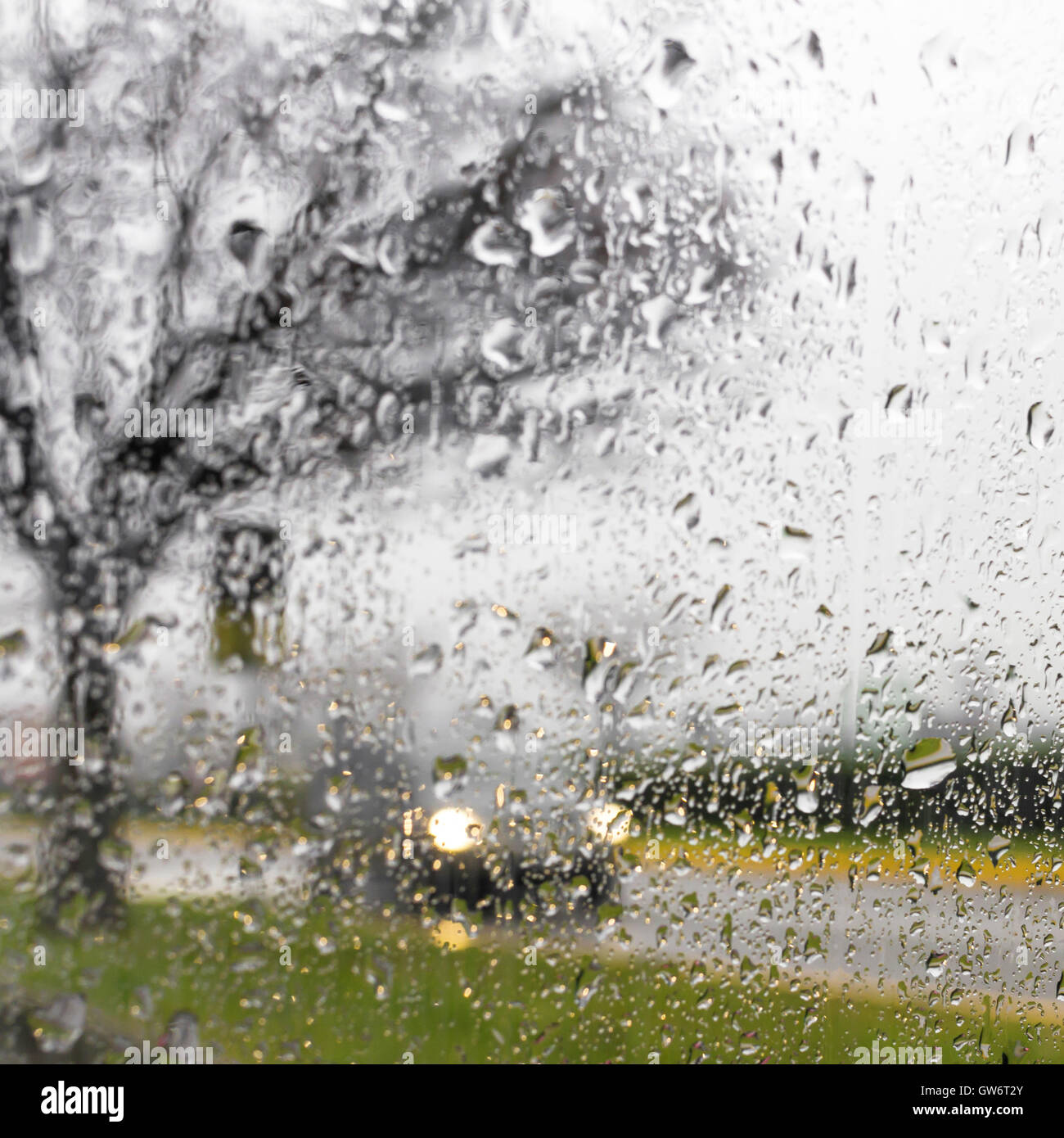 Blurry car silhouette seen through water drops on the car windshield ...