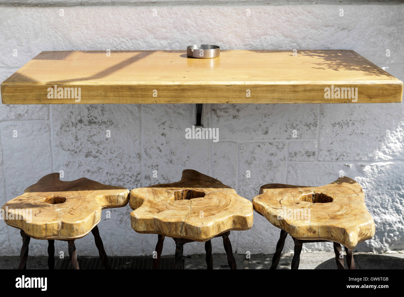 Bar table with three wooden stools and white wall Stock Photo - Alamy