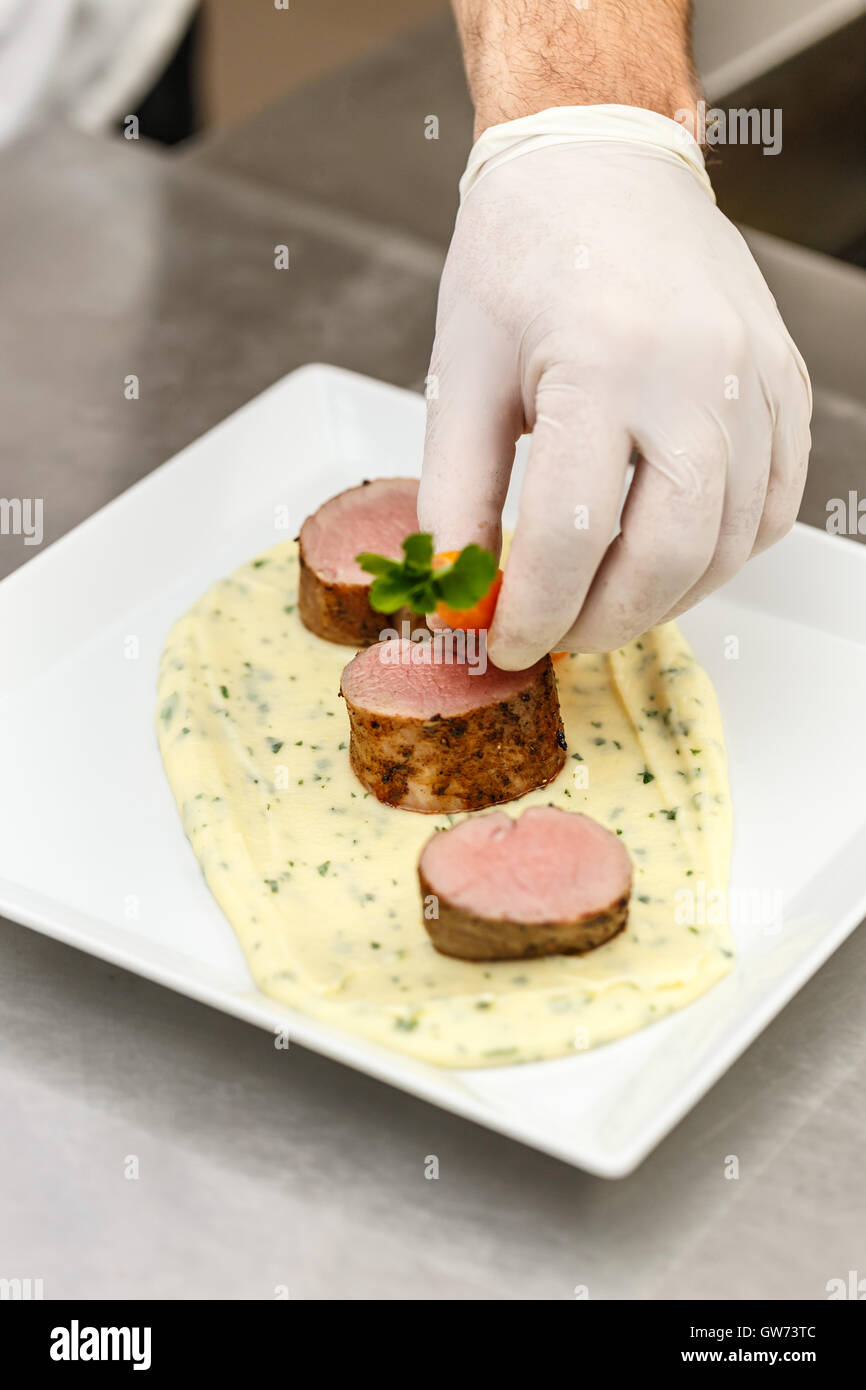 Chef garnishing meat plate in commercial kitchen Stock Photo - Alamy