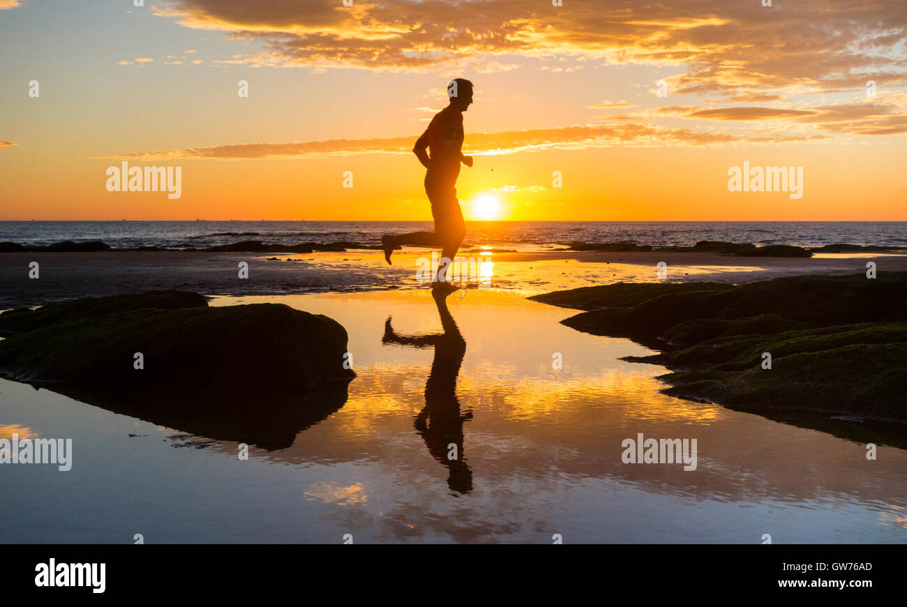 Man Jogging on beach at sunrise Stock Photo - Alamy