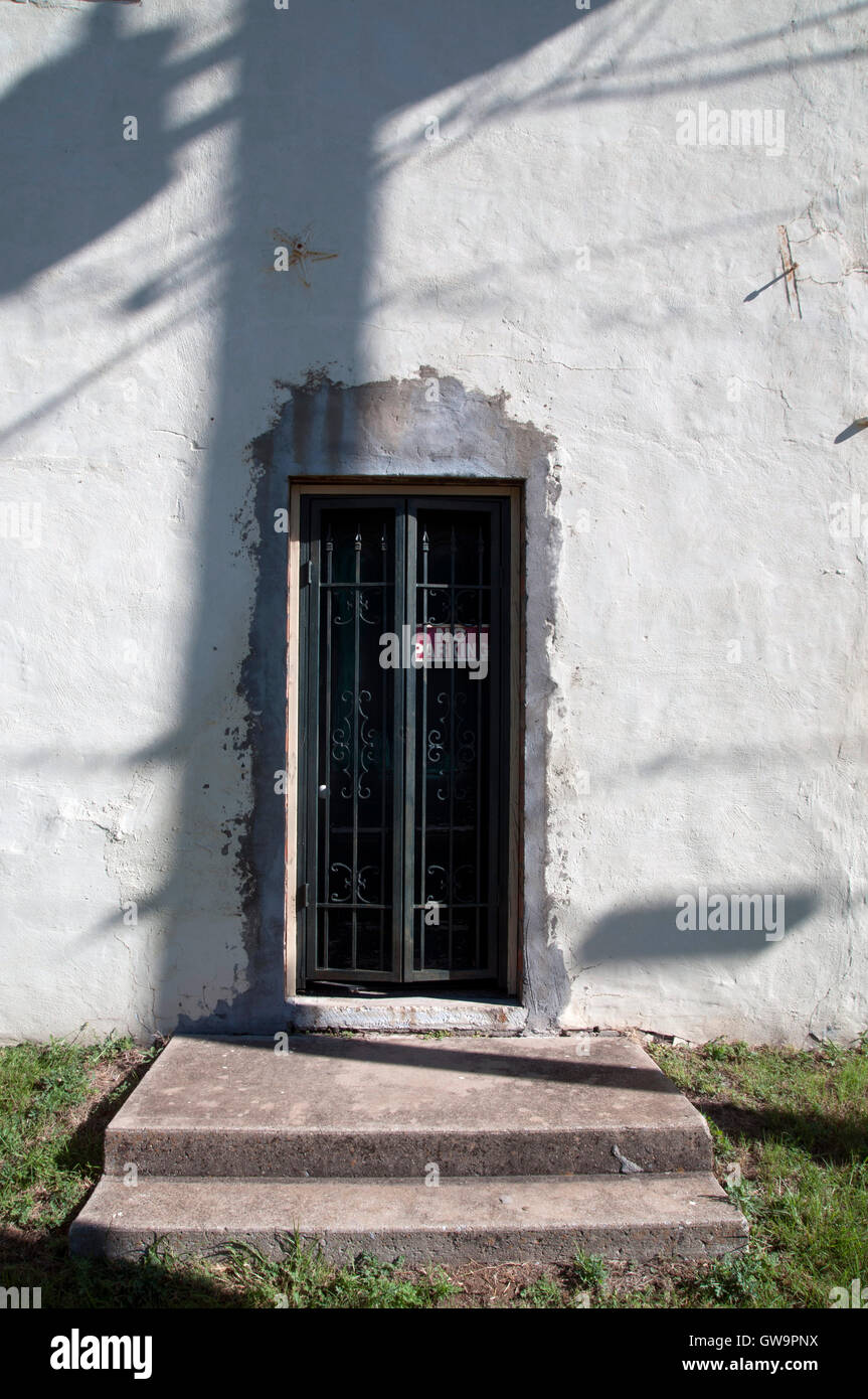 Distressed door behind an iron security gate with a "No Parking" sign ...