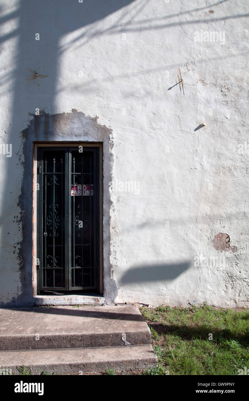 Distressed door behind an iron security gate with a "No Parking" sign ...